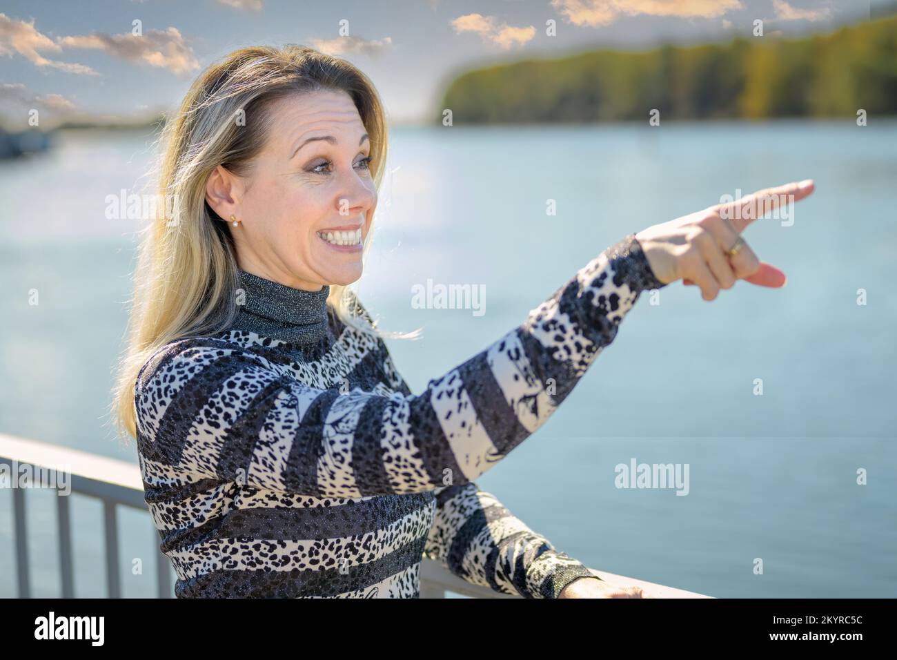 Side view of a beautiful funny woman with a bright smile pointing at ...