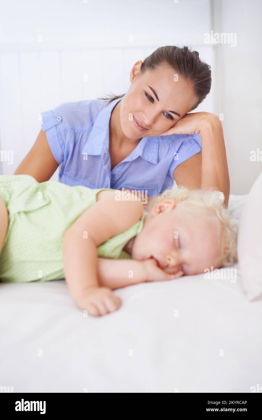 Motherly love. a mother watching over her sleeping child Stock Photo ...