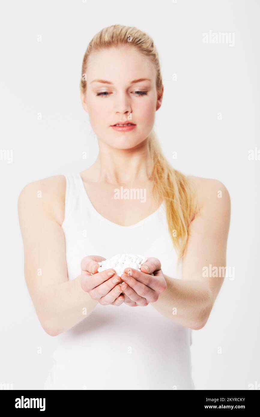 Under The Medication Spell A Girl Holding A Hand Full Of Pills Against An Isolated Background