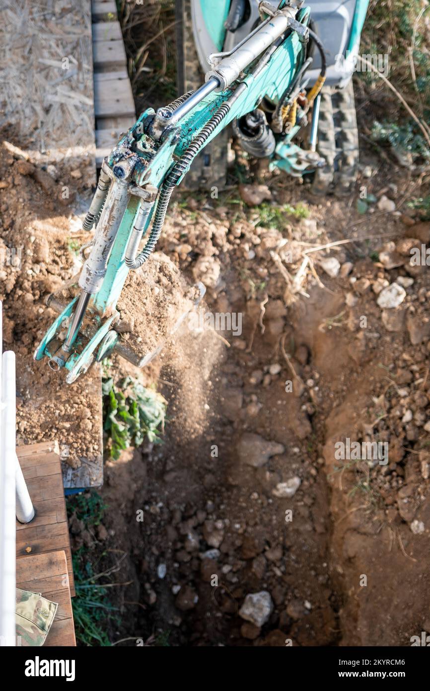 Mini excavator digs a trench to lay pipes. Close up of an excavator ...