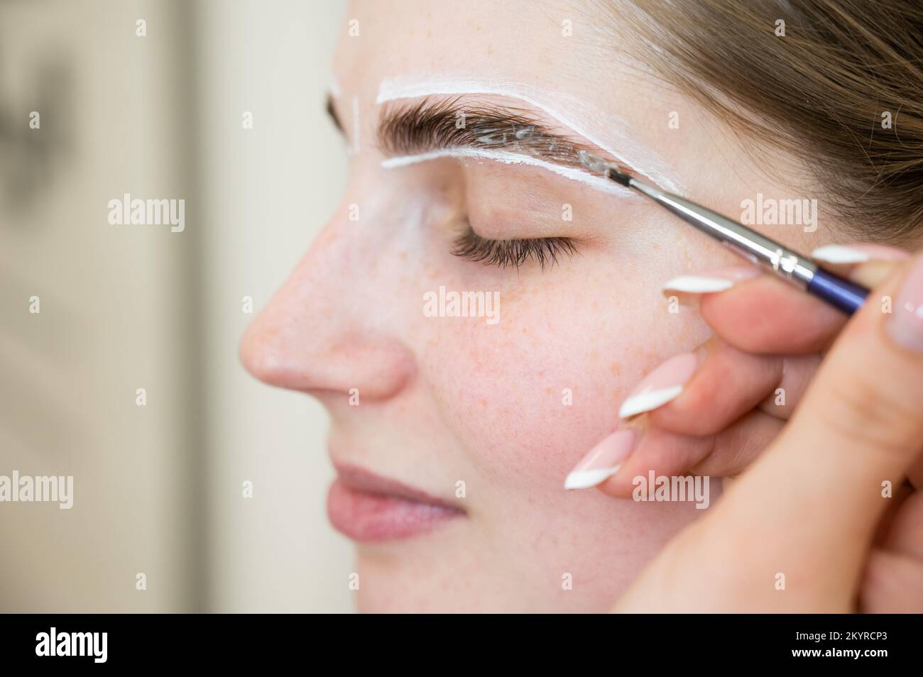 The master draws the shape of the eyebrows with white paint before ...