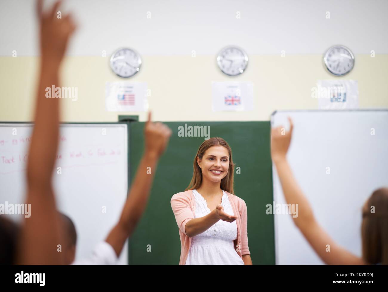 Go ahead...Rearview shot of a group of students raising their hands ...