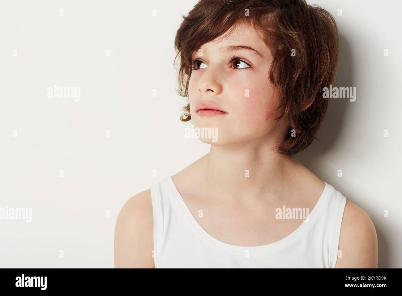 Pensive and casual. Preteen boy wearing a vest while isolated on white ...