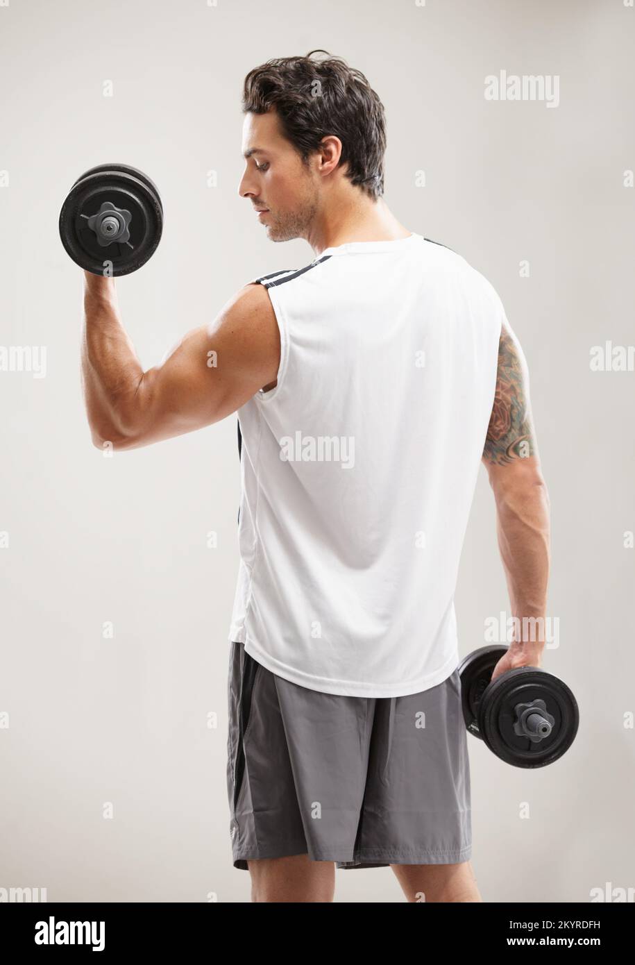 Getting in shape one rep at a time. A handsome young man doing bicep ...