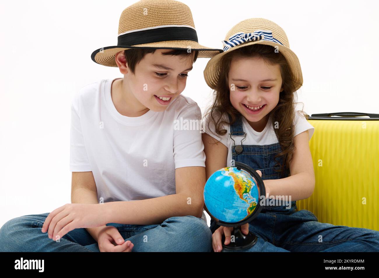 Happy boy and girl point fingers at a place on a globe with Earth map ...