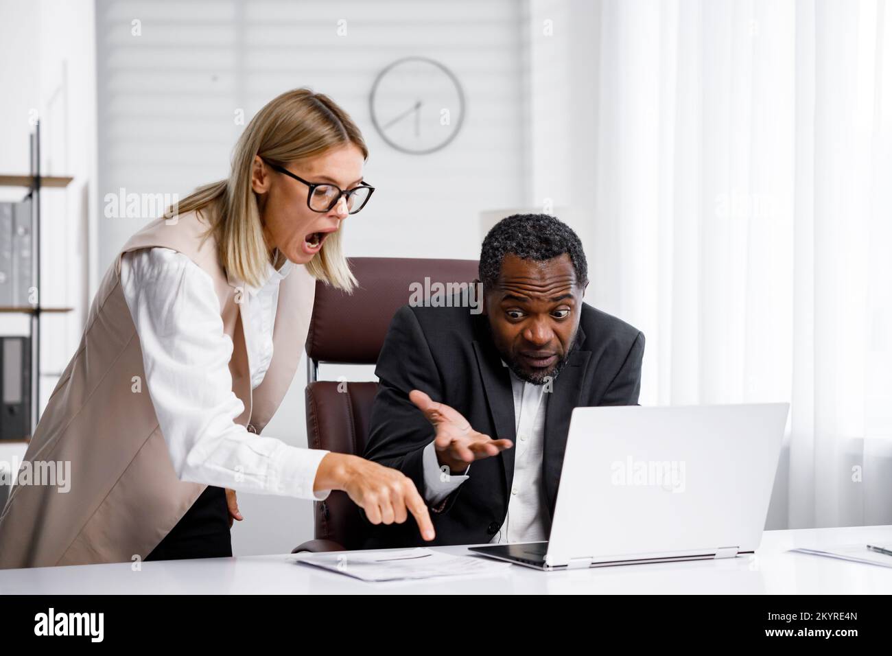 Angry female boss scolding African American office worker. A demanding ...