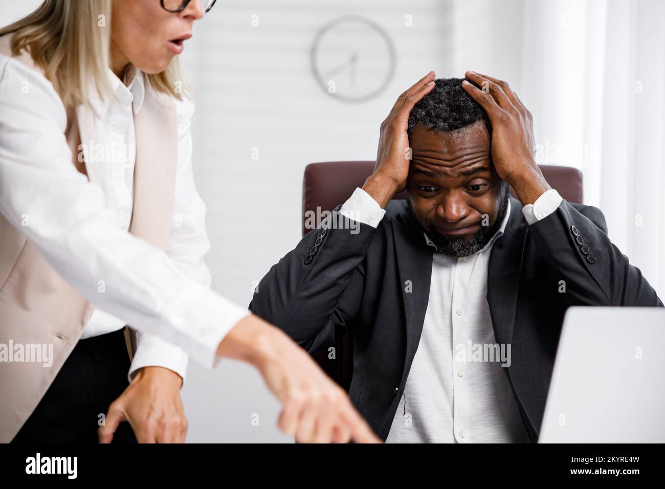 Angry female boss scolding African American office worker. A demanding ...