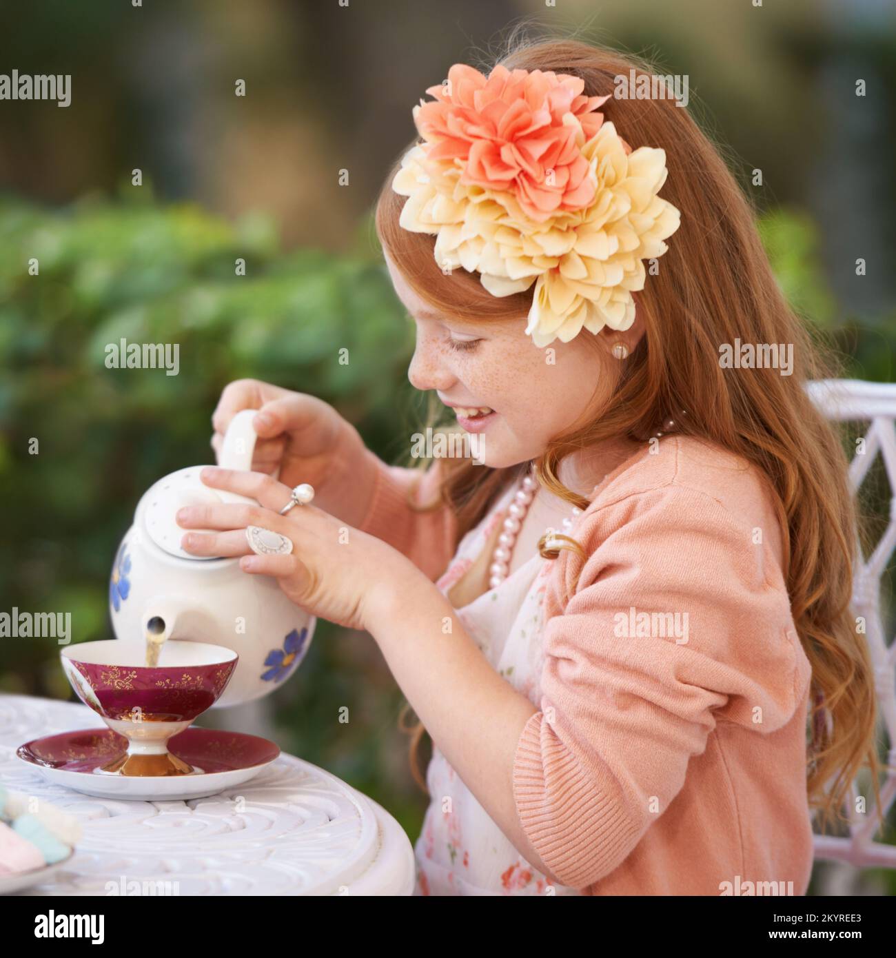 Hosting her tea party. A cute little girl having a tea party outside ...