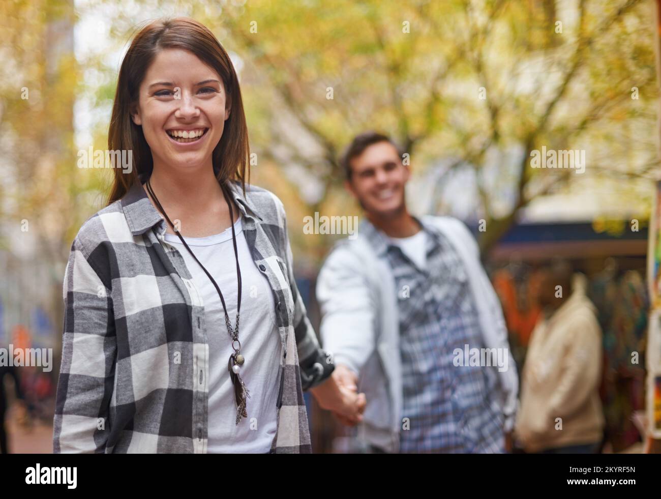 Taking a stroll through town. A young couple walking hand in hand through town Stock Photo - Alamy