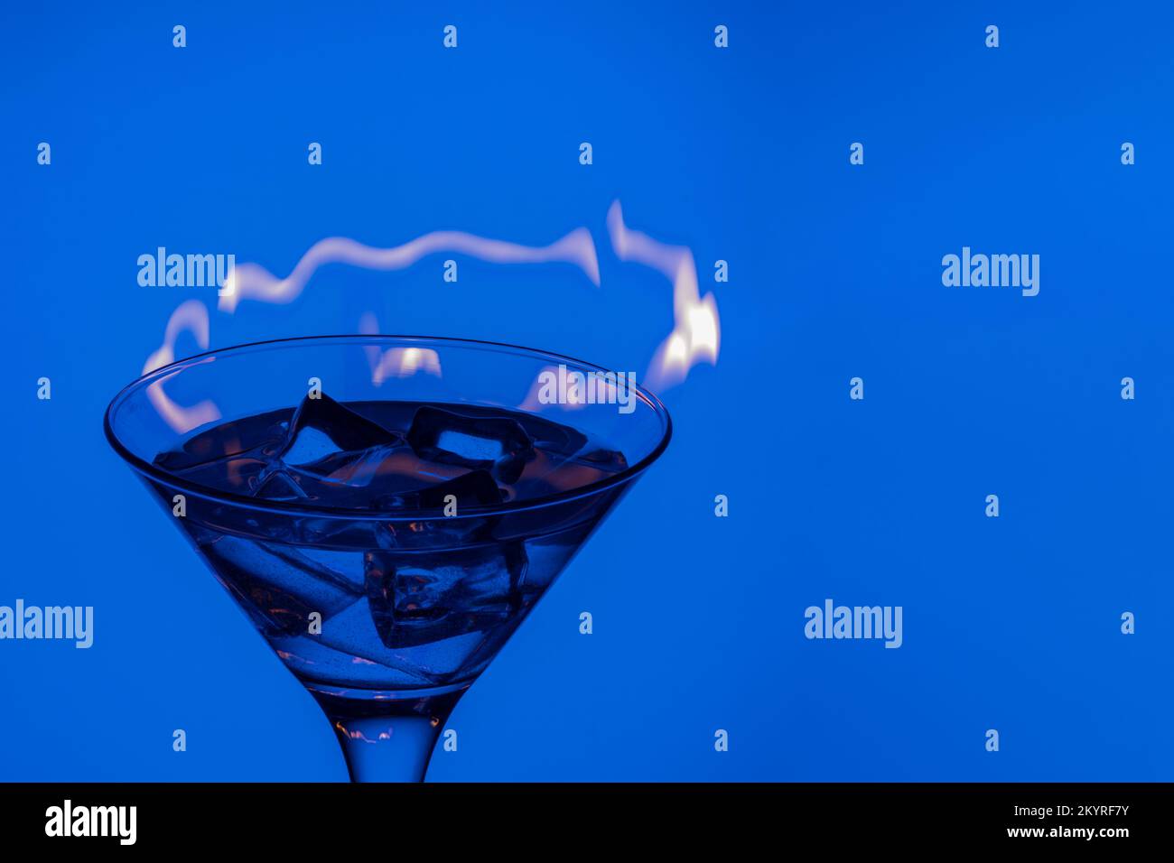 Burning alcoholic drink with ice cubes, on a blue gradient background ...