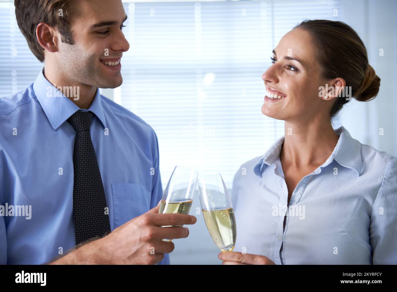 Heres to a job well done. Two colleagues toasting with a glass of ...