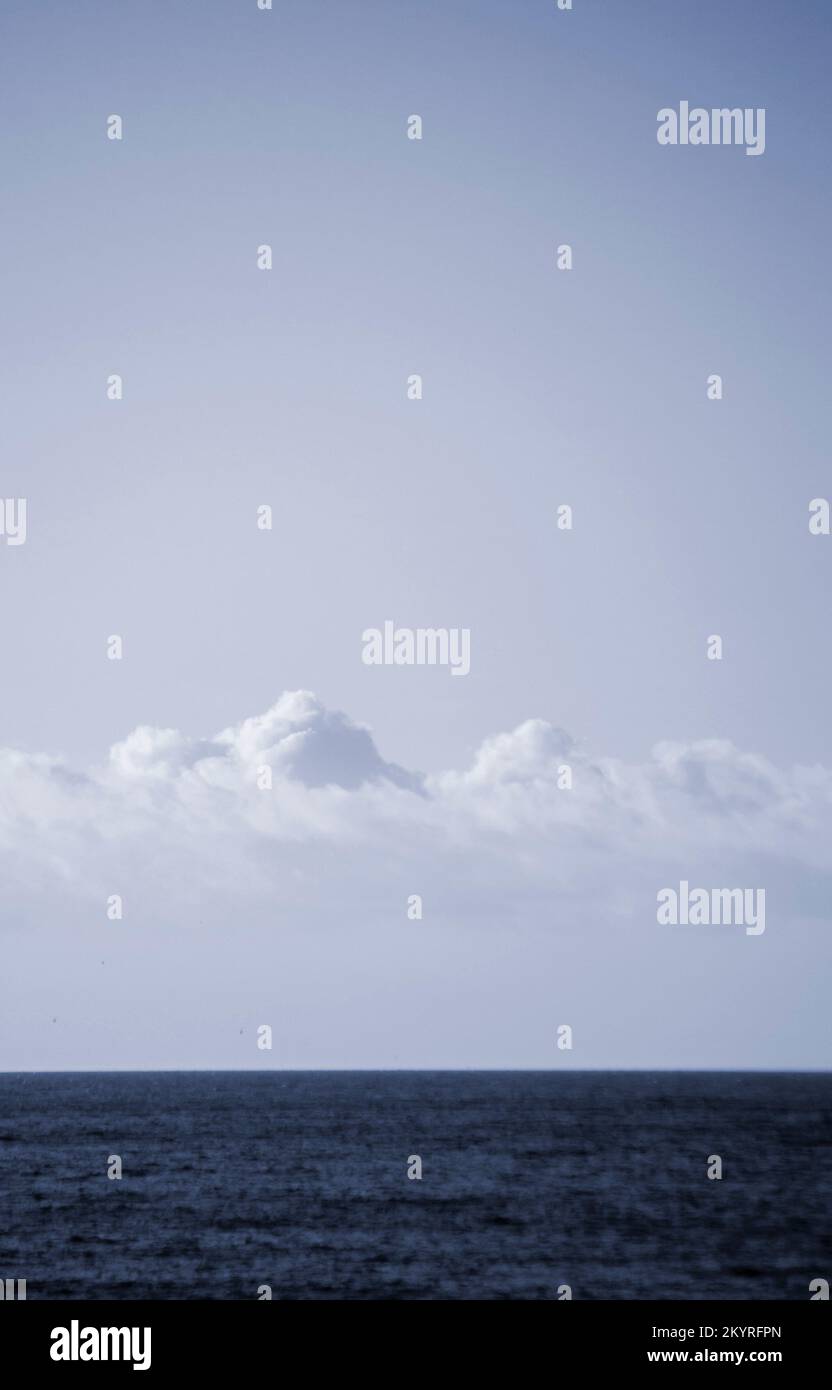 White cumulus clouds over the blue surface of the sea on sunny day. Beautiful natural background ...