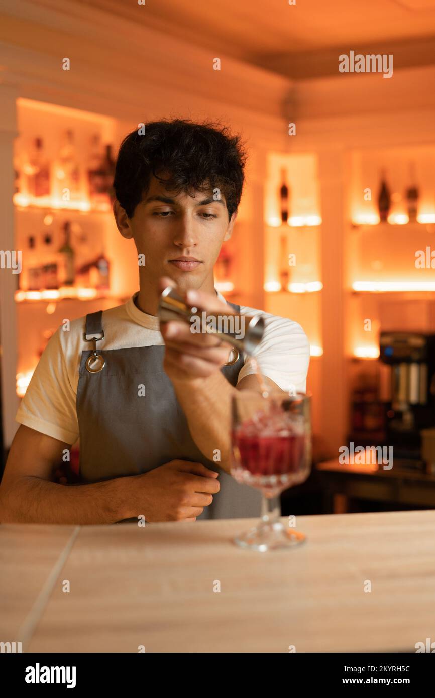 Bartender Pouring Alcohol Into Glass With Ice Using Beaker On Bar