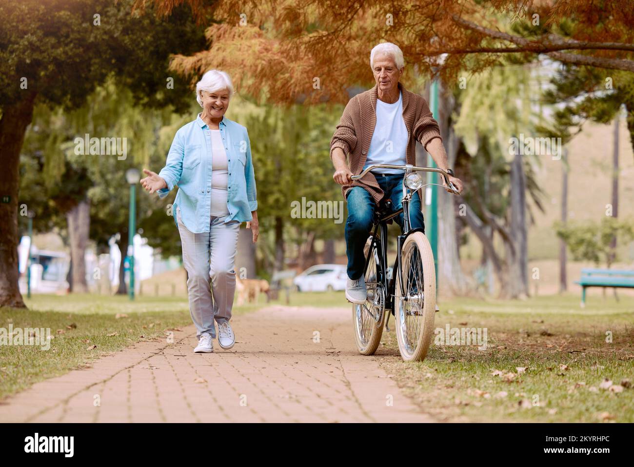 Senior couple, walking and bike at park, talking and bonding together ...