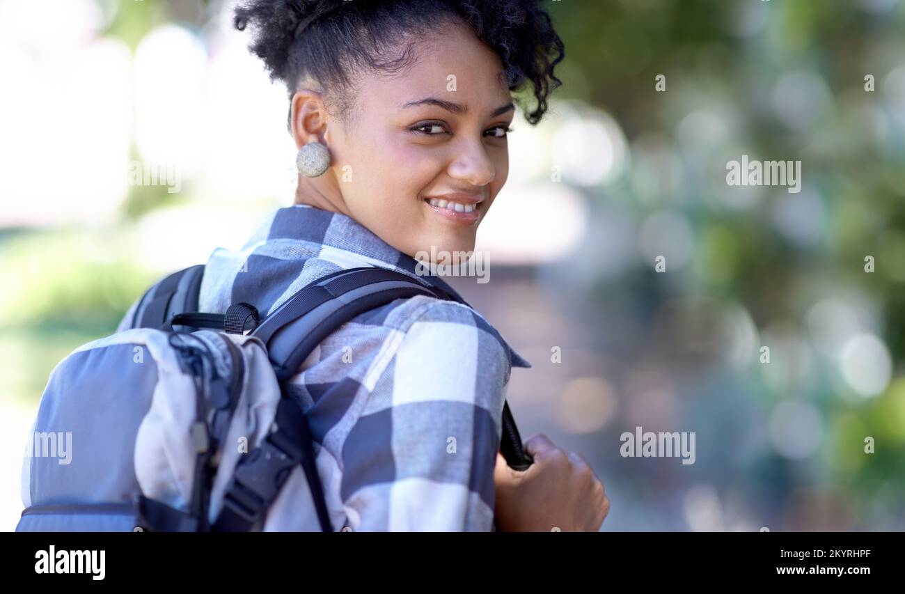 Flashing a genuine smile. An attractive young college student standing ...