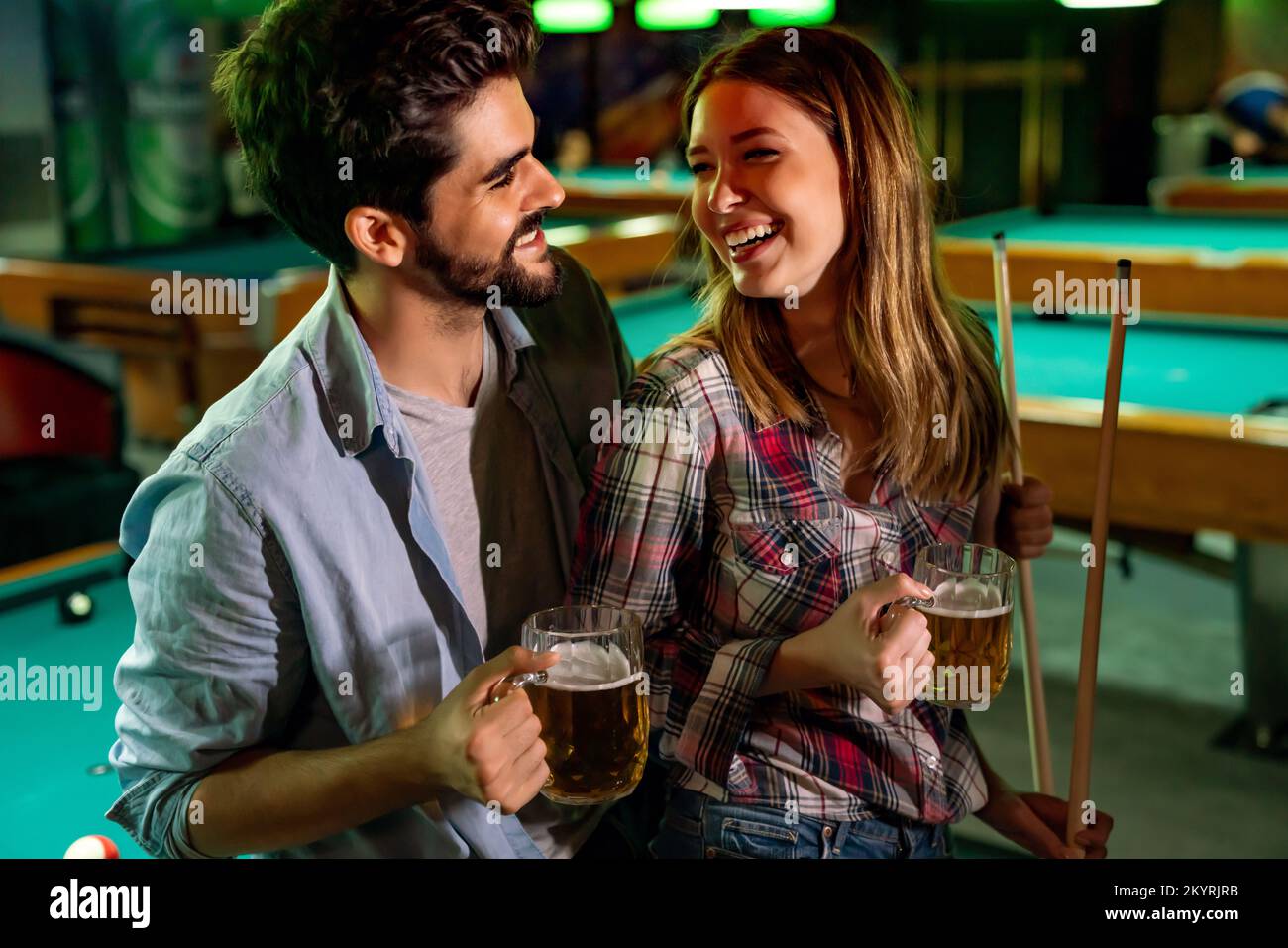Happy young couple enjoying while playing billiard in bar. People ...