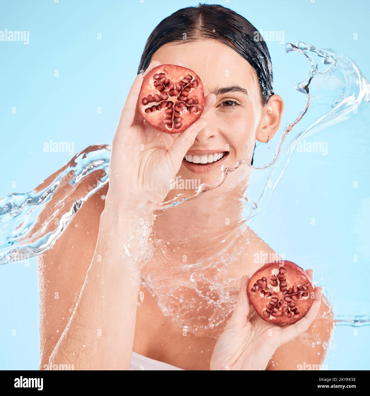 Face, pomegranate and skincare woman in water splash studio for nutrition, detox or vitamin c ...