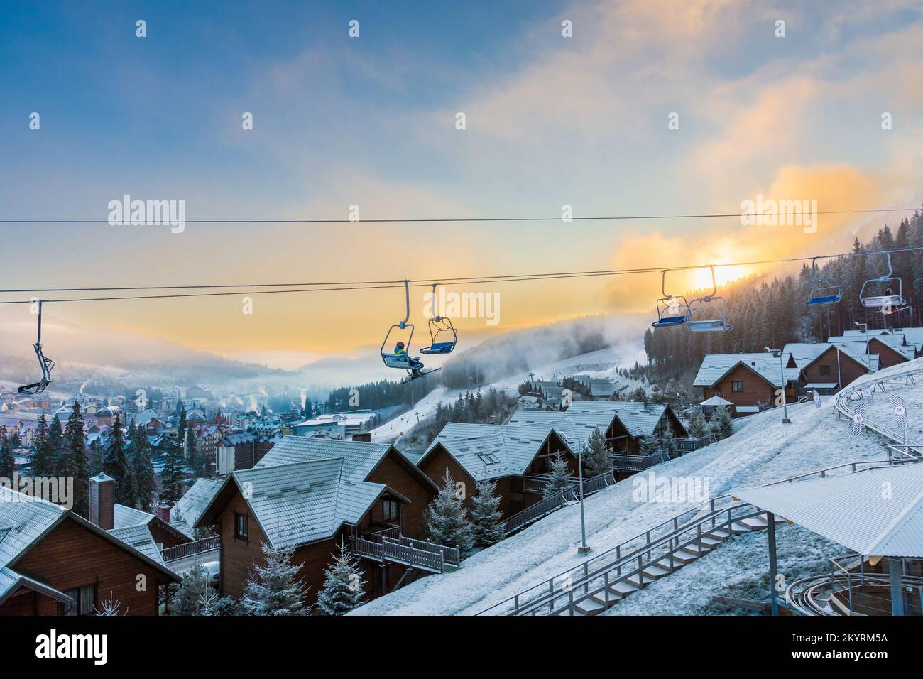 Ski resort in beautiful sunset light. View from the top: ski tracks ...