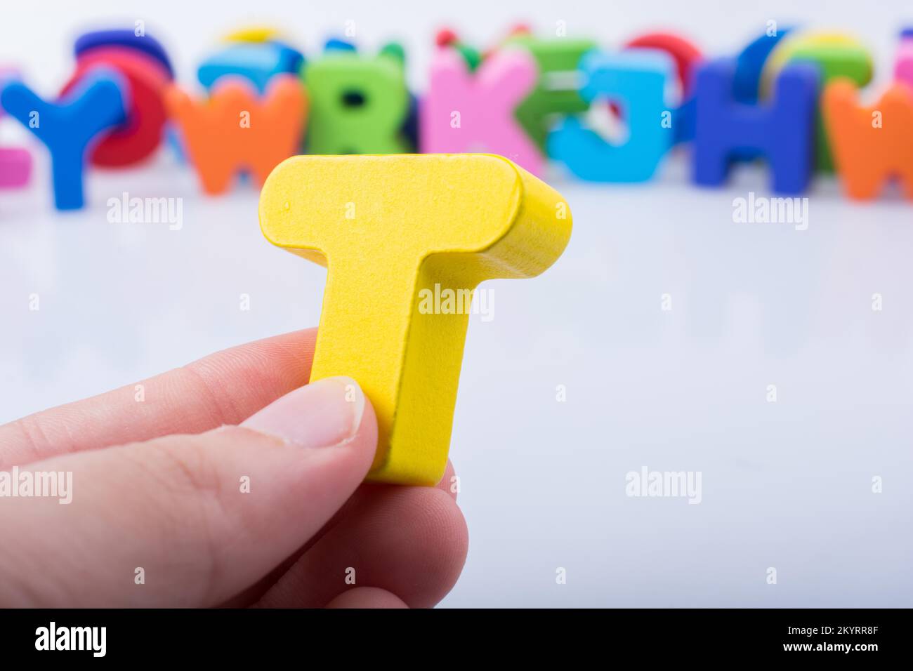 Hand holding letter cube T of made of wood Stock Photo - Alamy