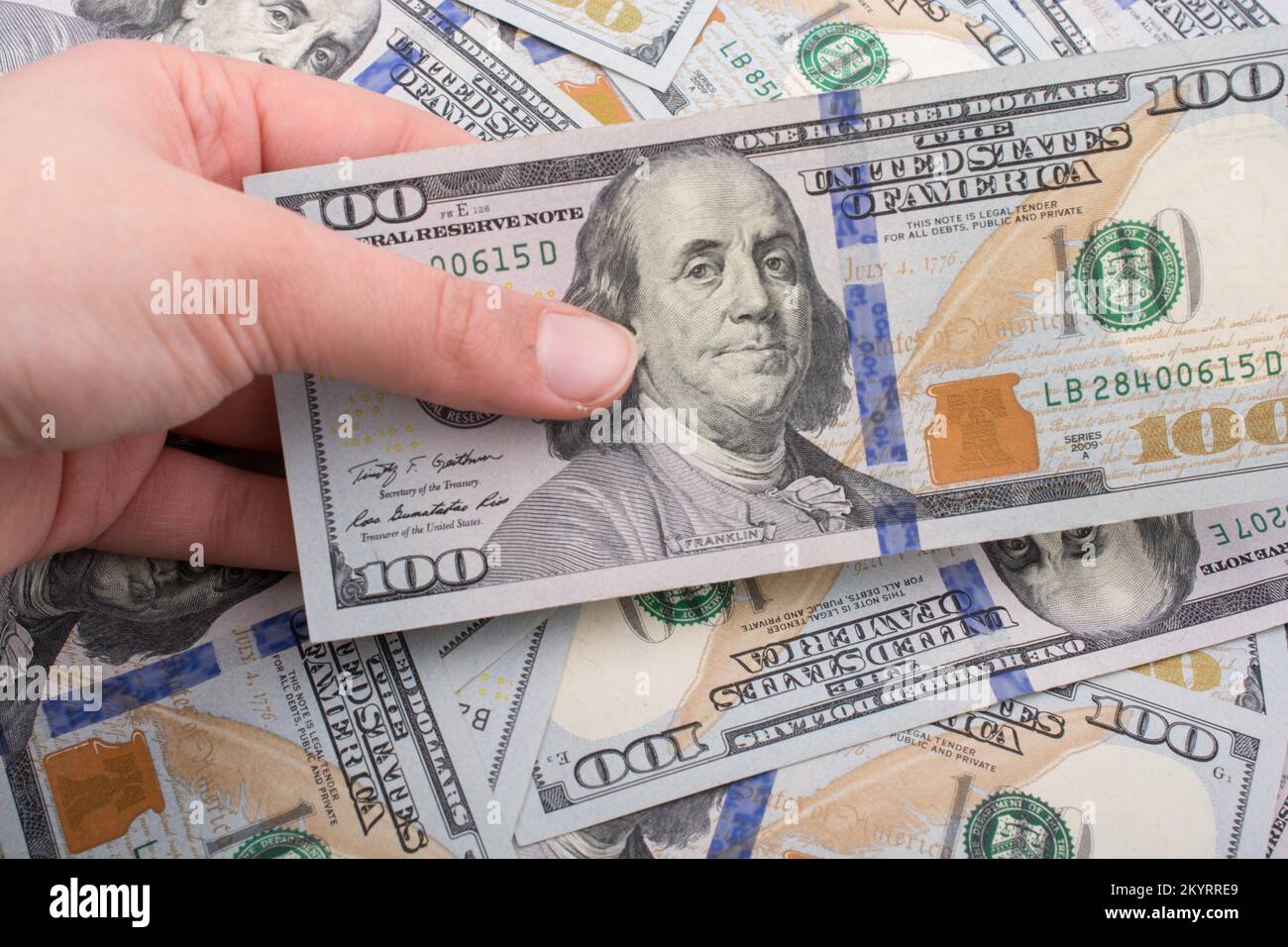 Hand holding banknotes on other banknotes of US dollar spread around ...