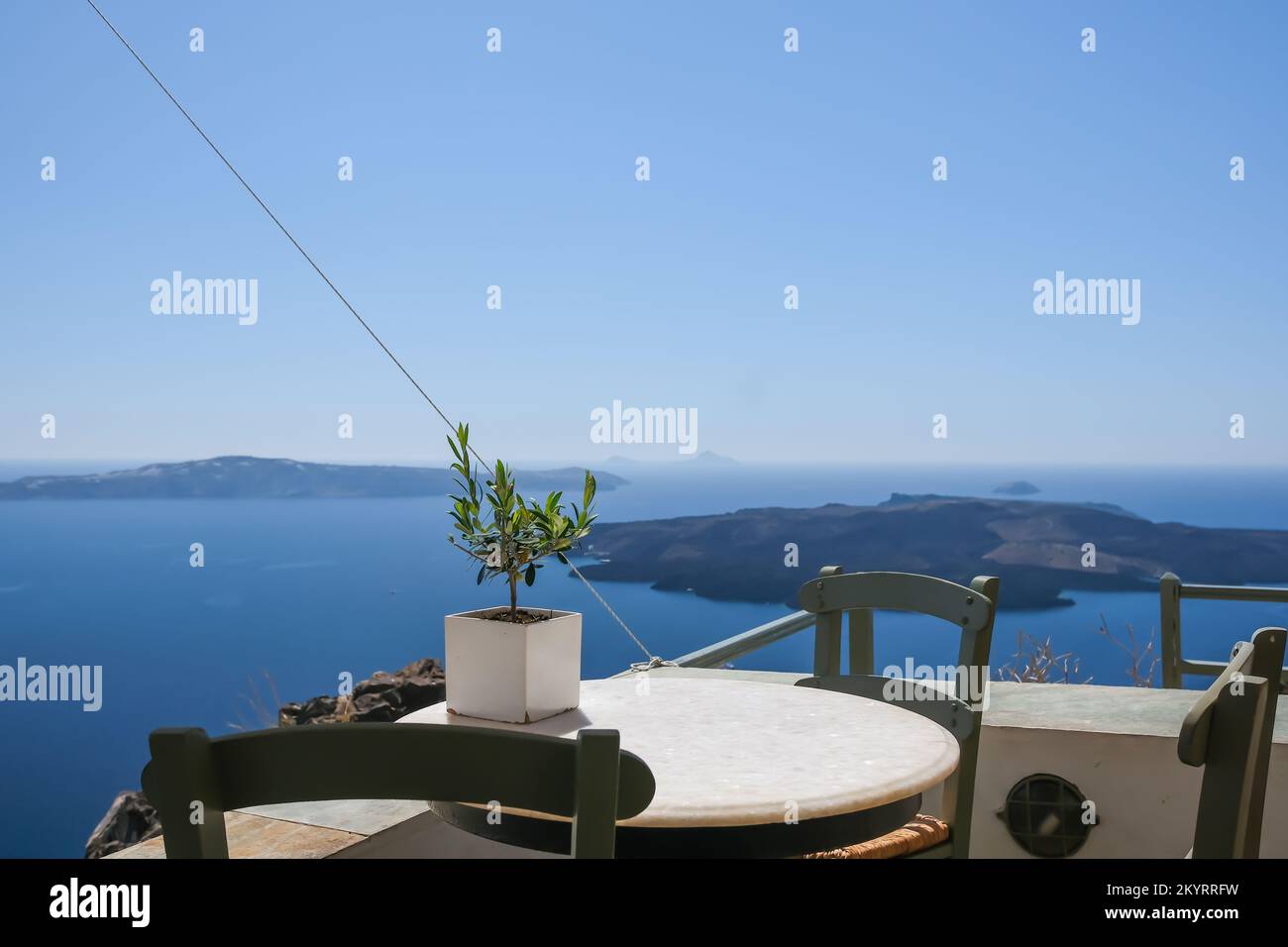 View of a table with chairs decorated with a small olive tree in a vase ...