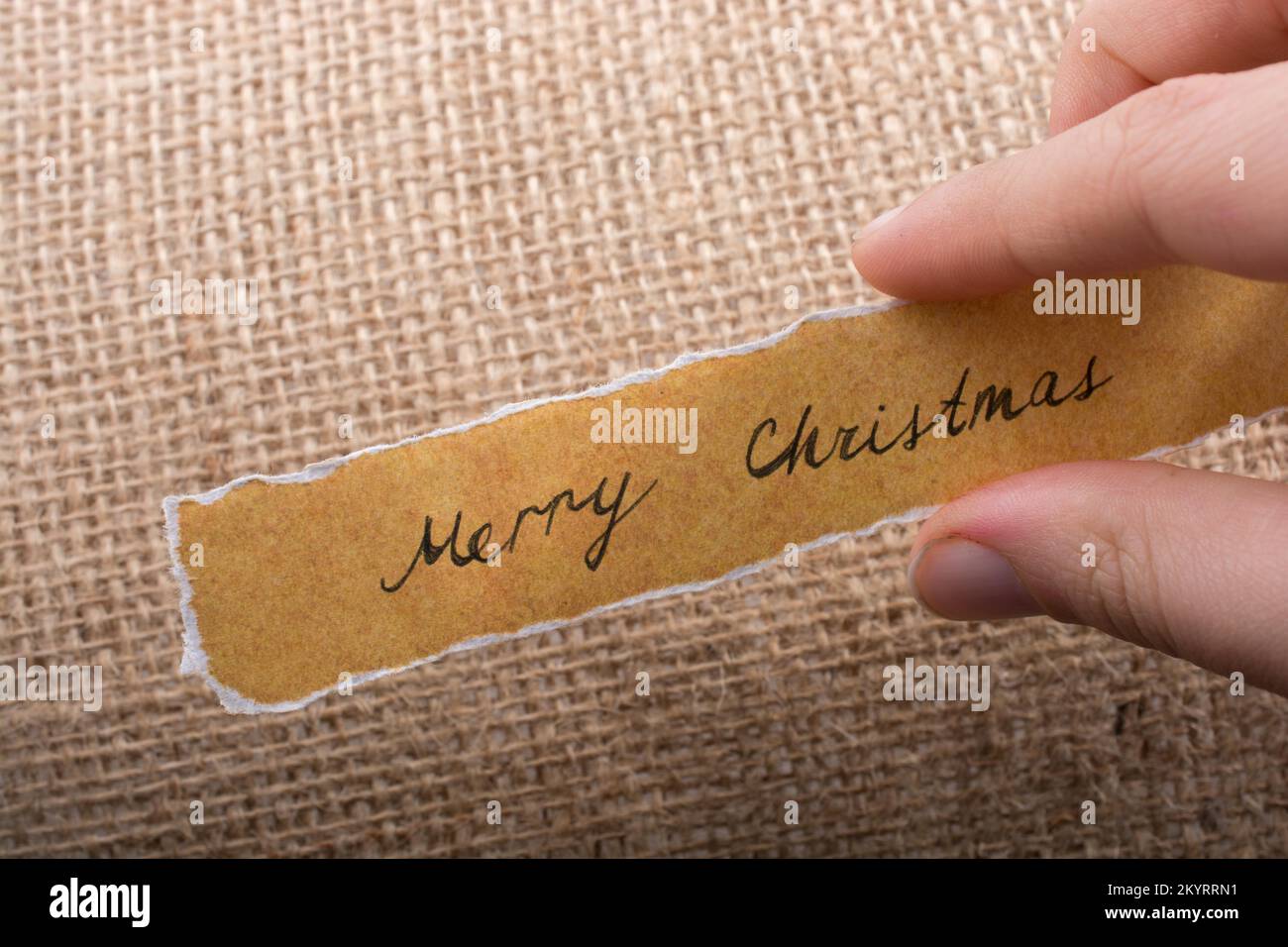 Merry Christmas wording written on a torn paper in hand Stock Photo - Alamy
