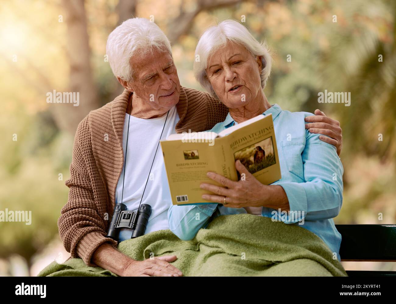 Park, senior and couple reading a book, relaxing and bonding outdoors ...