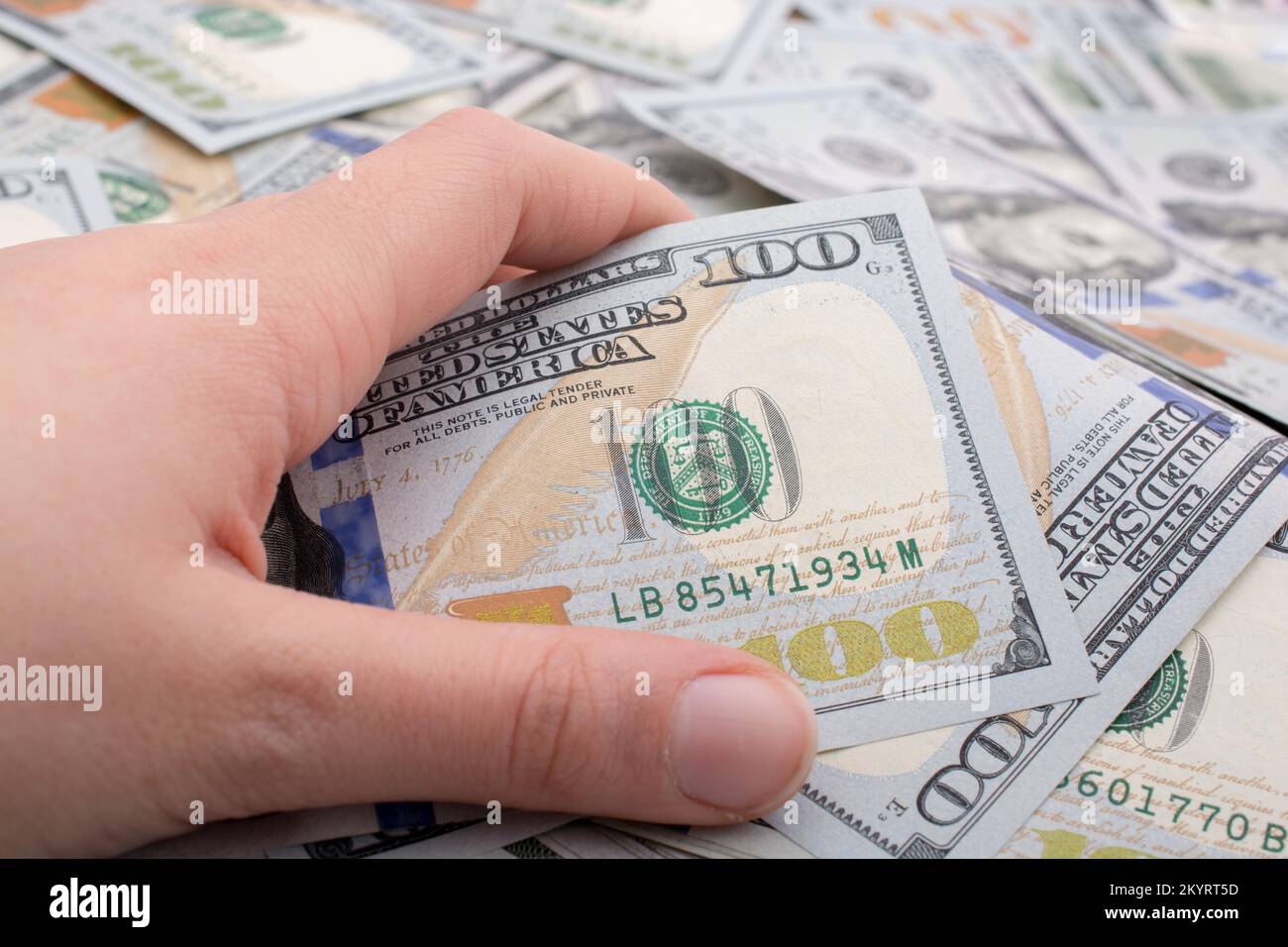 Hand holding banknotes on other banknotes of US dollar spread around ...
