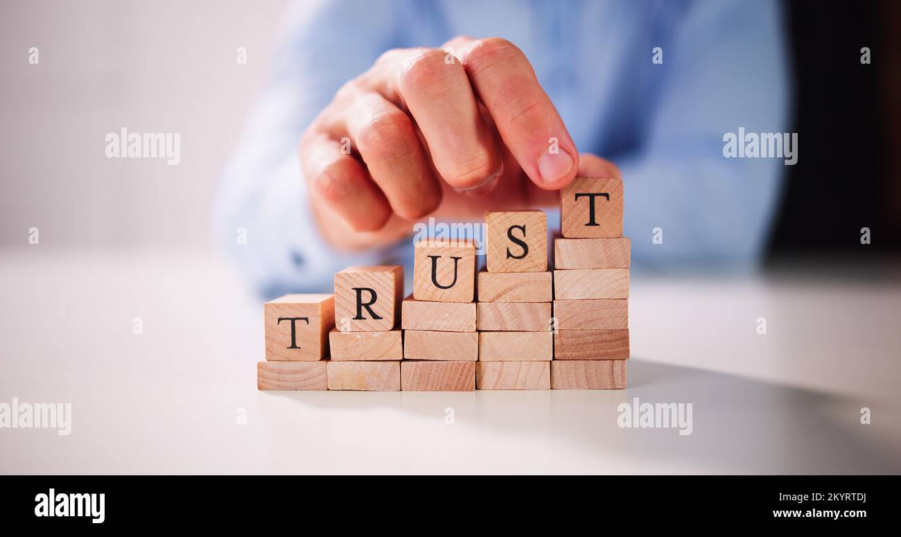 Man's Hand Placing Last Alphabet Of Word Trust Over Wooden Block Stock ...