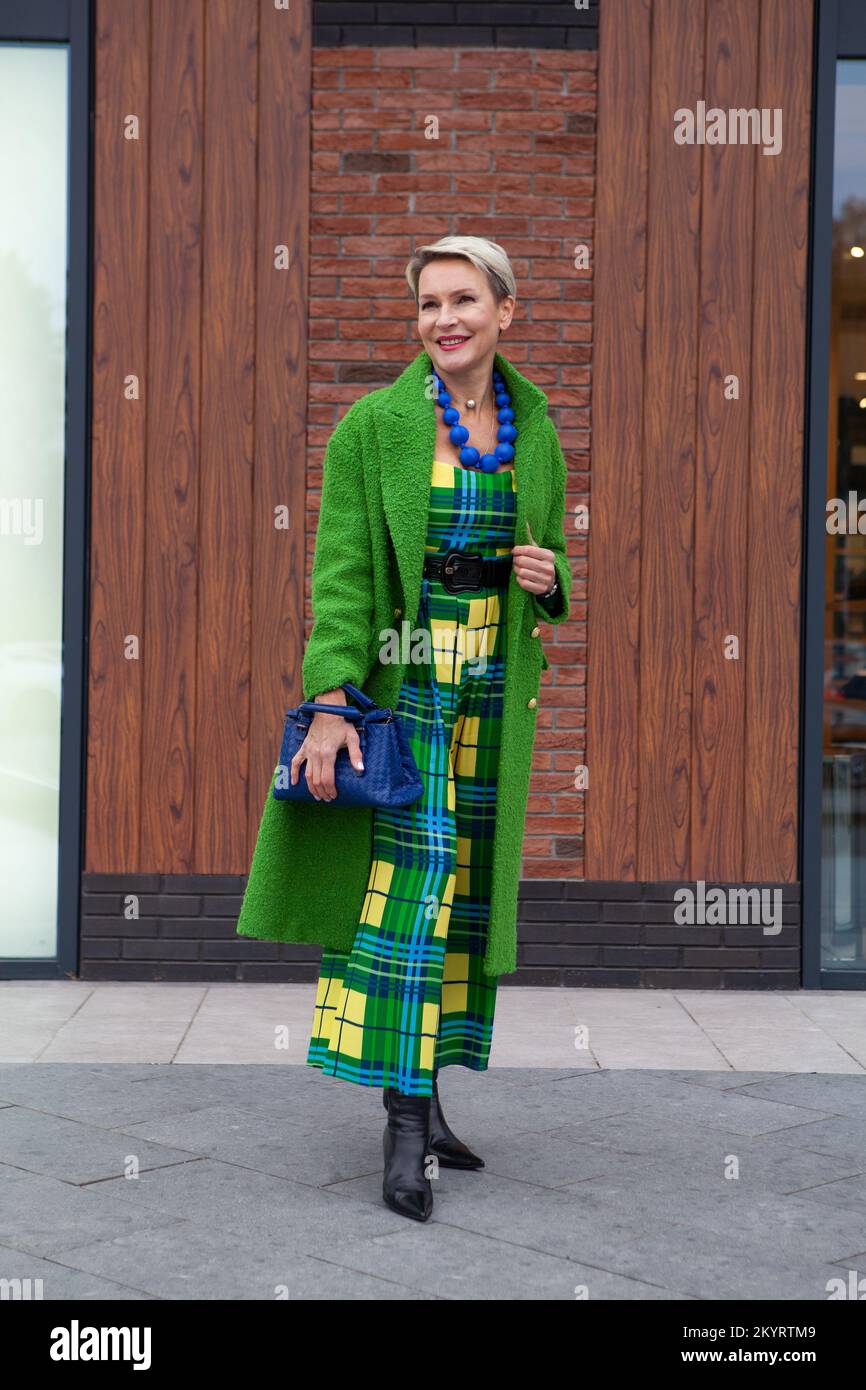 Full length portrait of fashionable aged woman in long green coat and ...