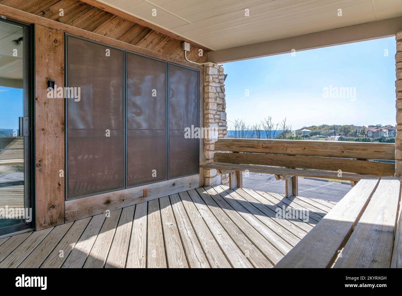 Balcony with wood floor and wooden seat overlooking an open parking lot ...