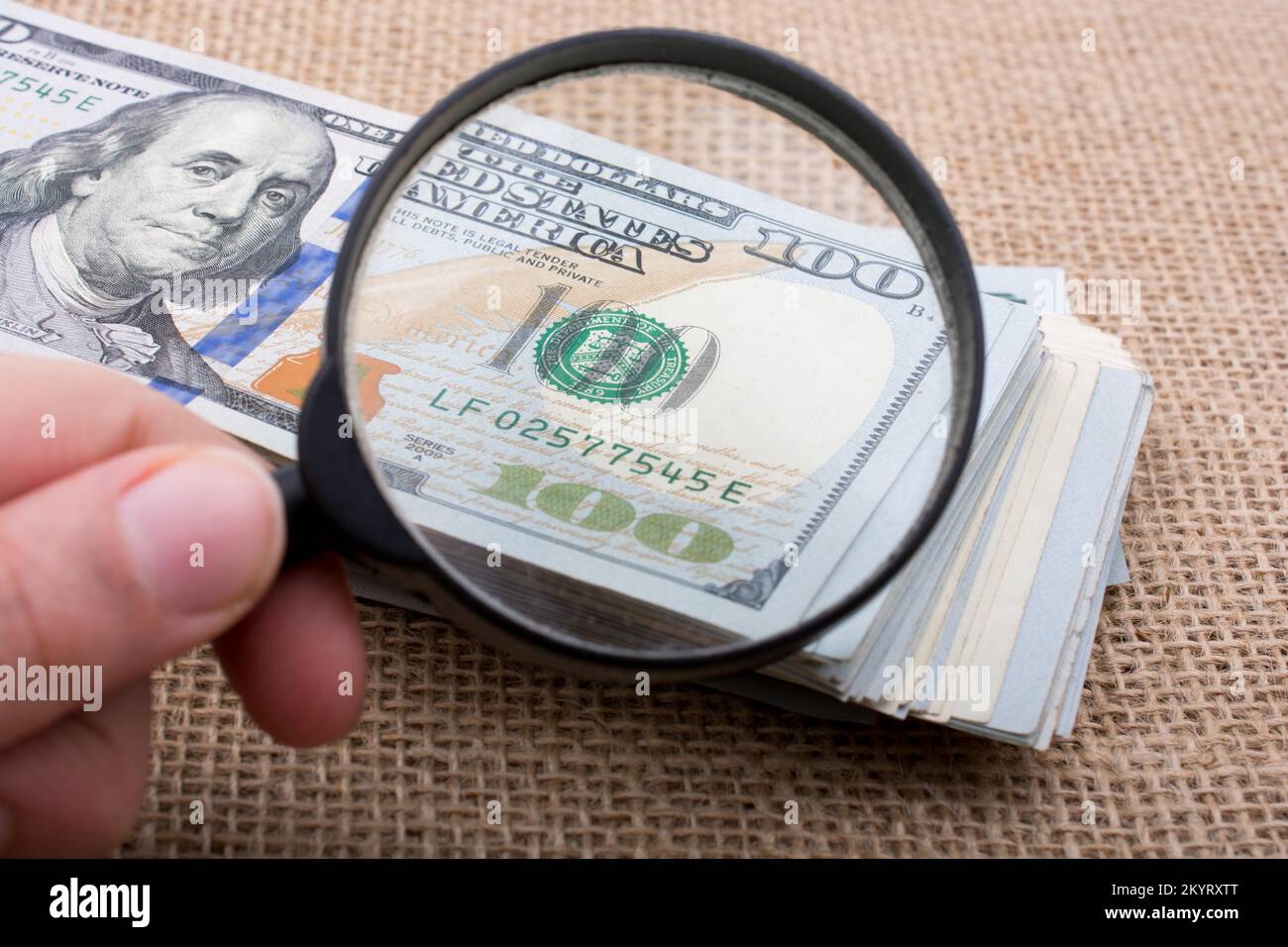 Magnifying glass is held over the banknote bundle of US dollar Stock ...