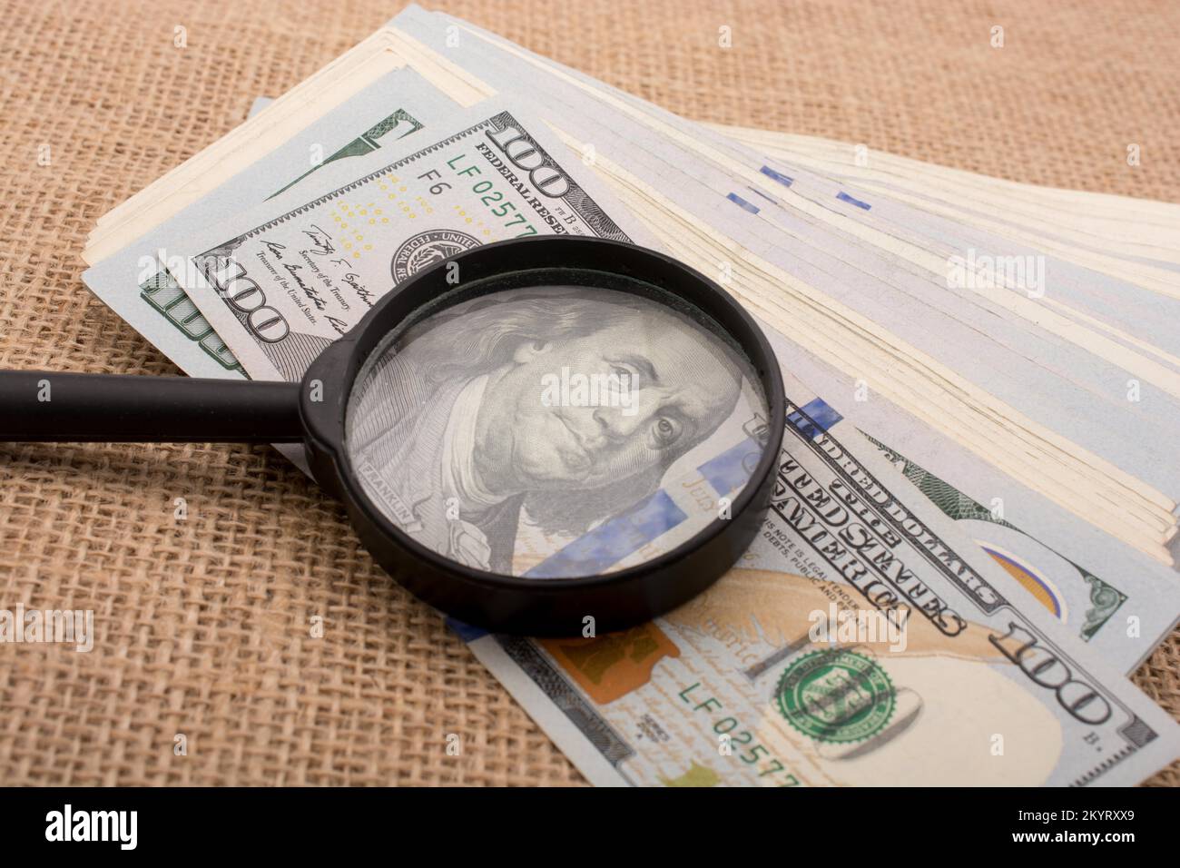 Magnifying glass is held over the banknote bundle of US dollar Stock ...