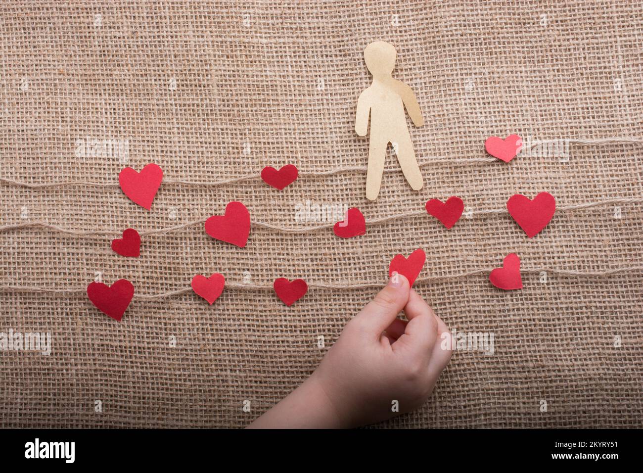Paper man and heart icons on linen threads on canvas Stock Photo - Alamy