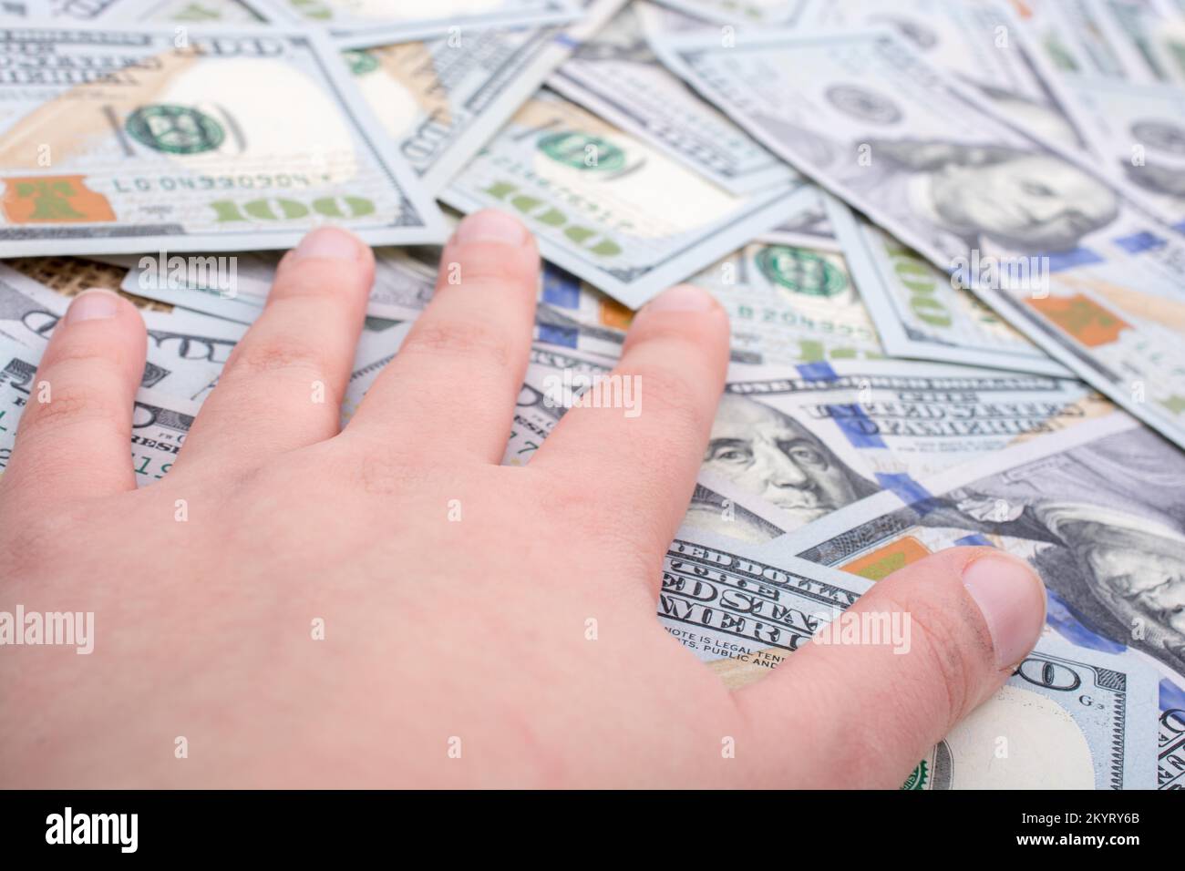 Hand holding banknotes on other banknotes of US dollar spread around ...