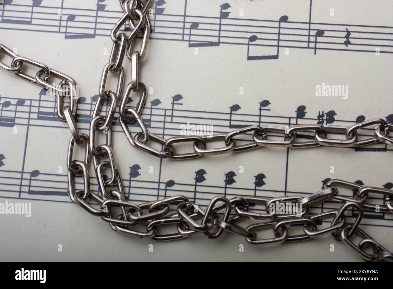 Metal chain placed on a paper with musical notes Stock Photo - Alamy
