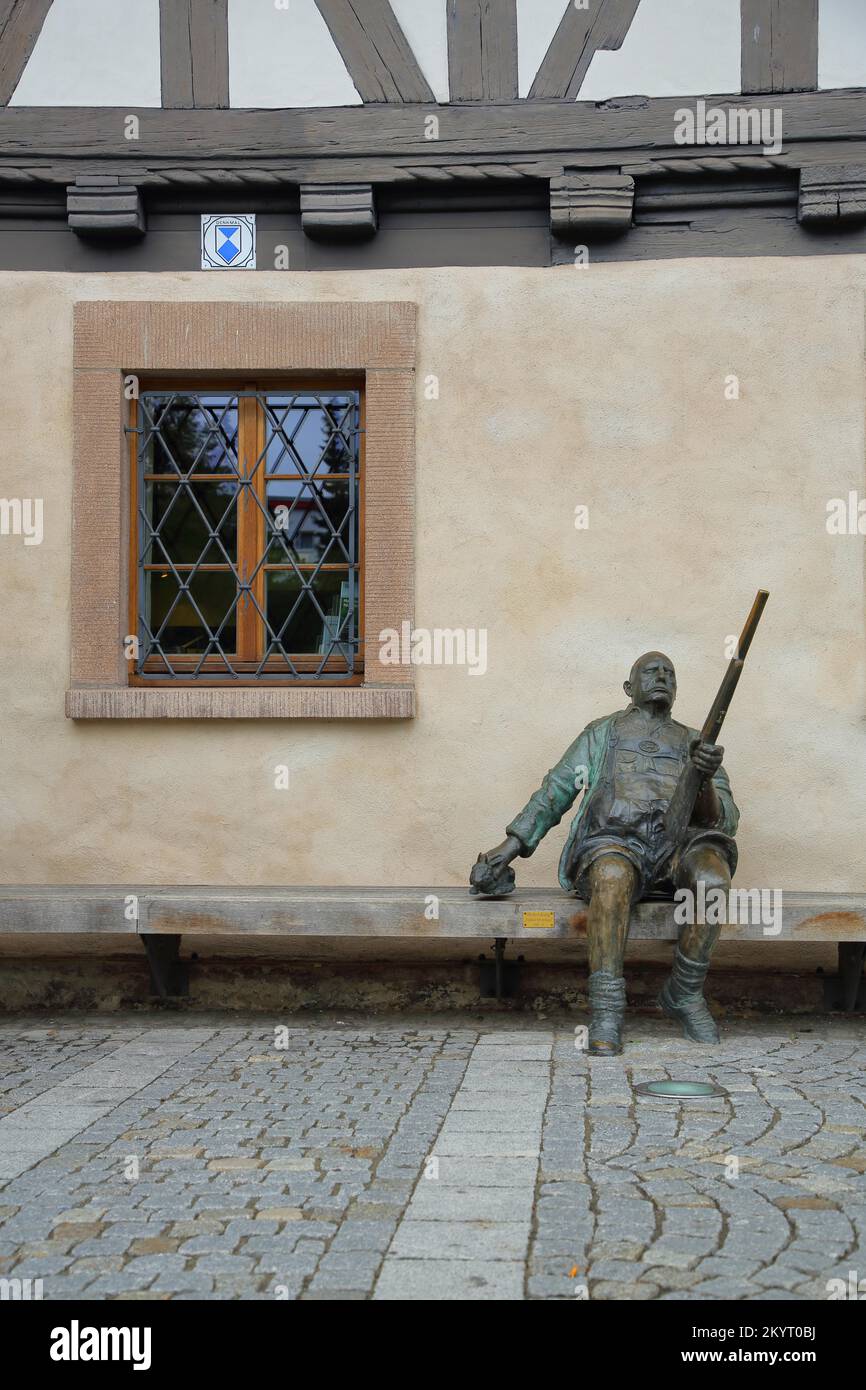 Sculpture Man sitting with rifle in front of half-timbered house ...