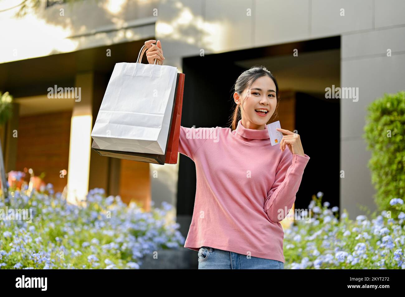Beautiful and charming young Asian woman carrying shopping bags and ...