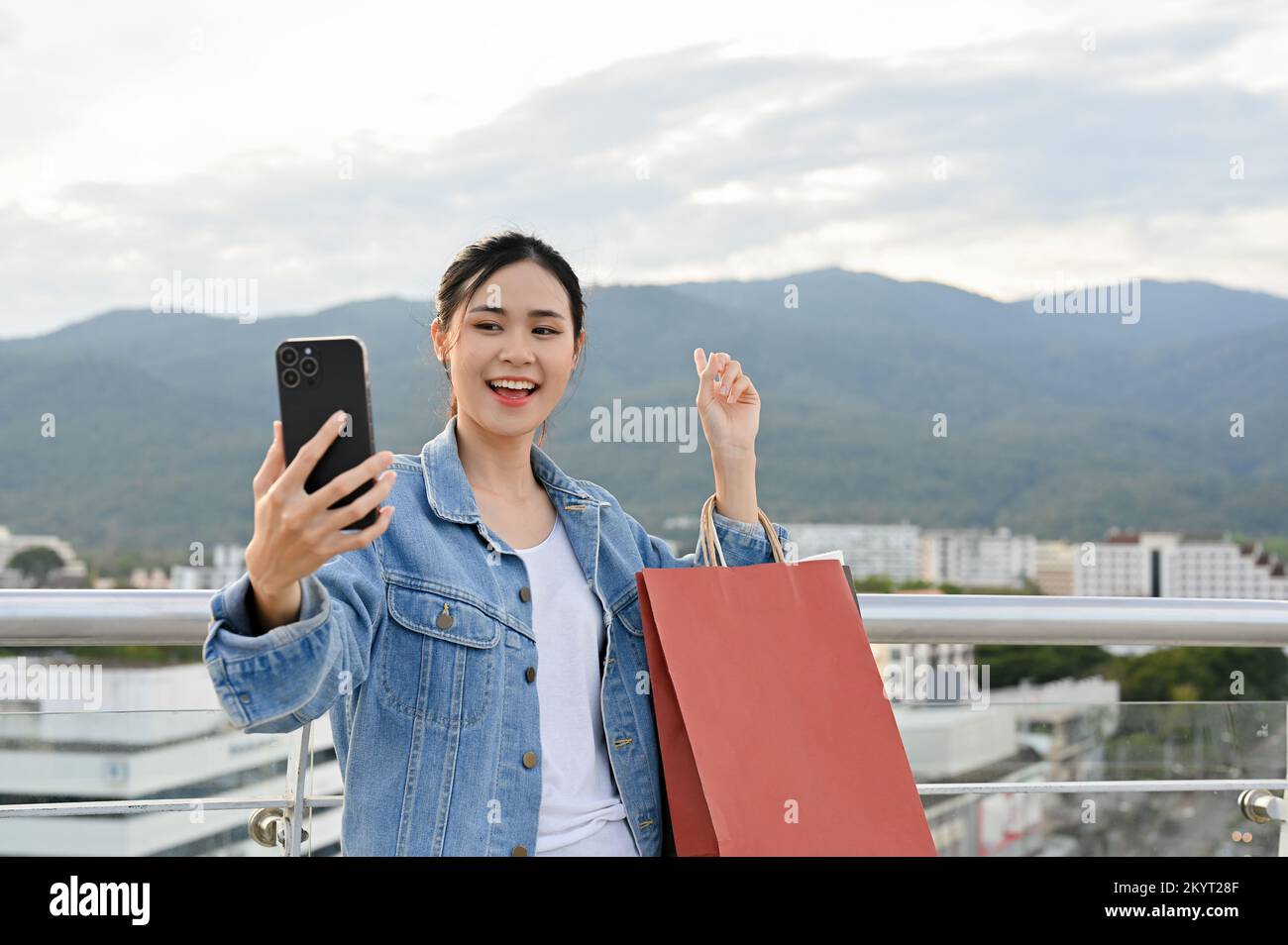 Happy and charming young Asian woman carrying her shopping bags, taking ...