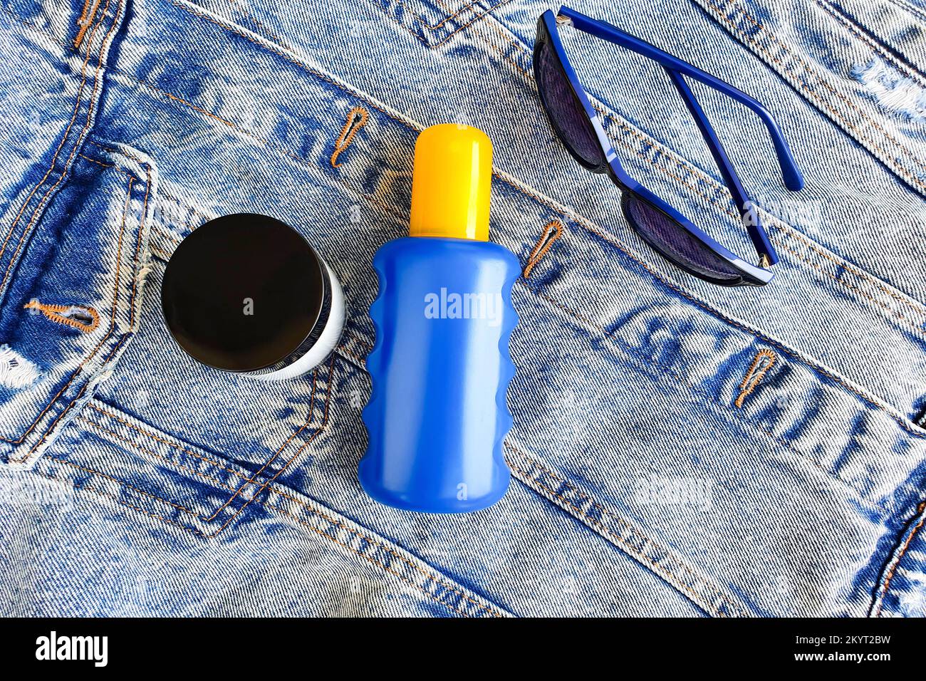 Blue cosmetic spray bottle with yellow cap, jar of cream with black cap ...