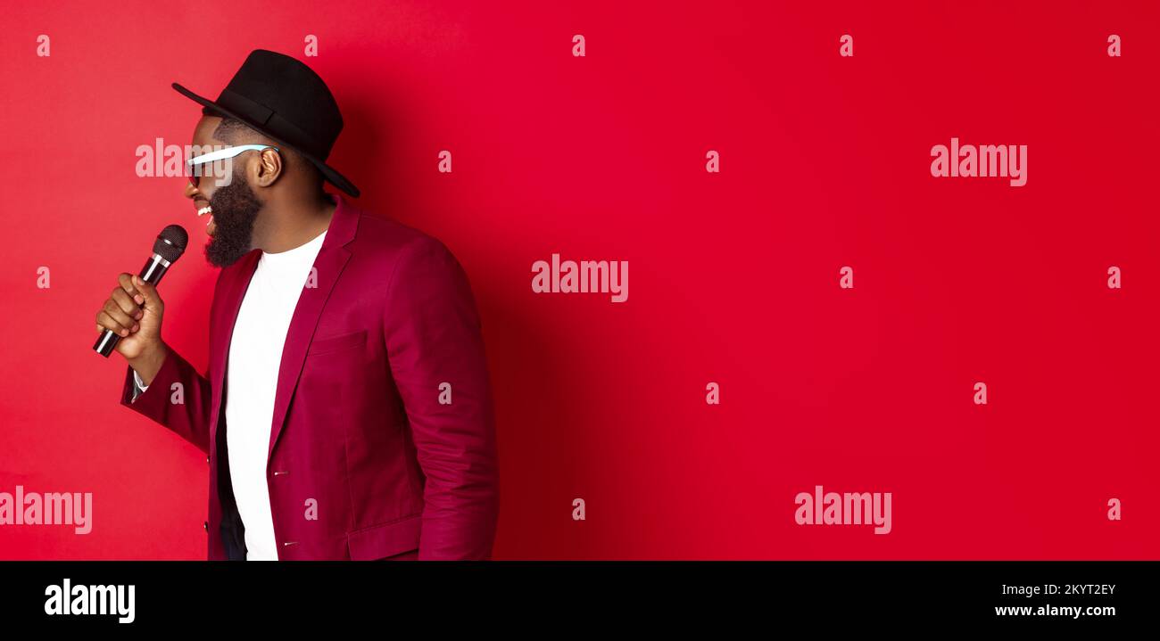 Passionate black male singer performing against red background, singing ...