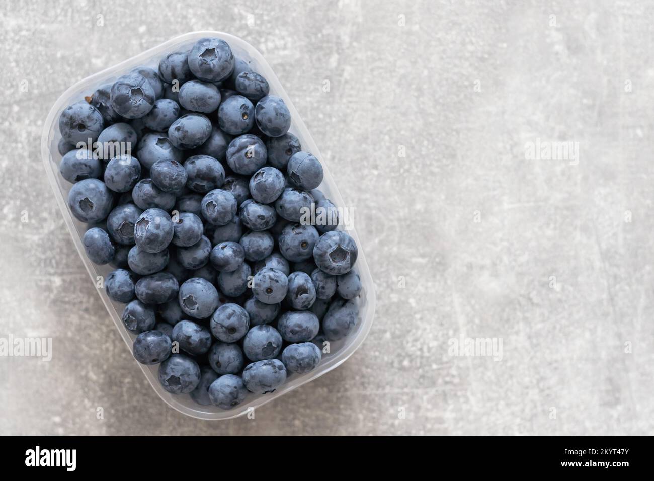 Freshly blueberry in a plastic box packed on a white background. space ...
