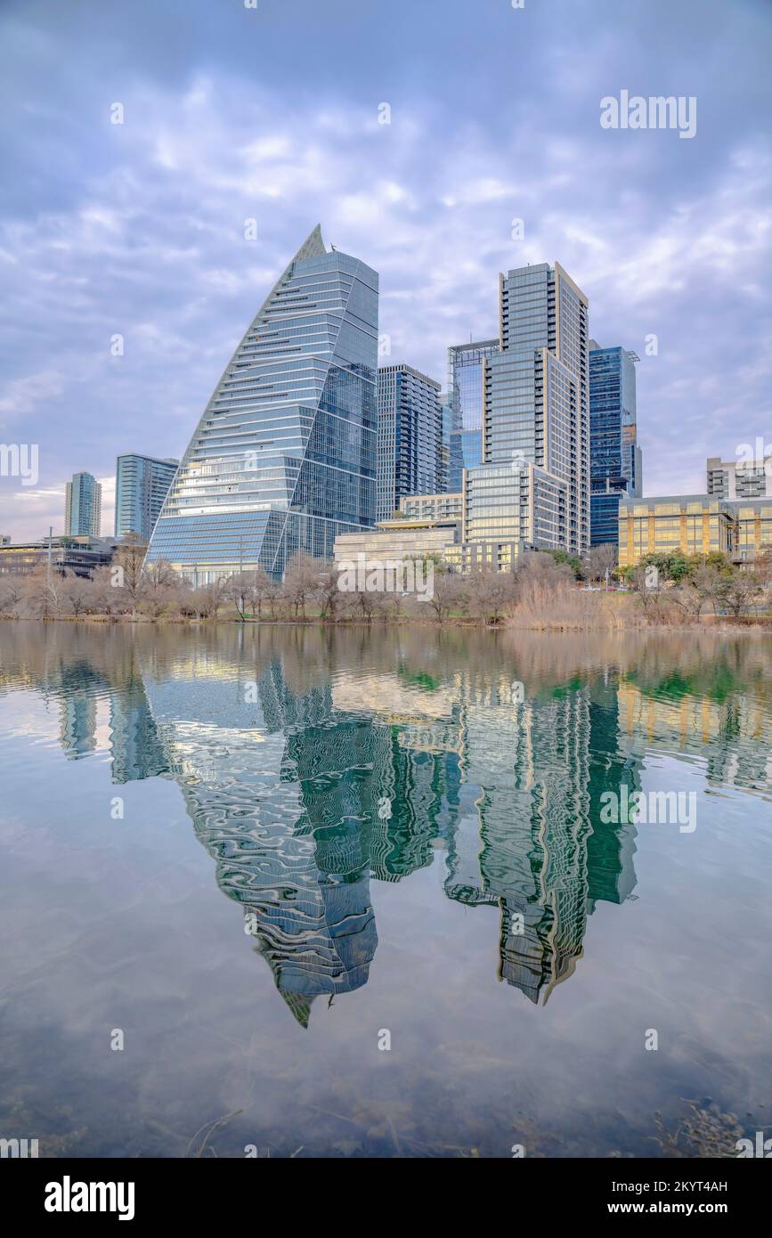 Modern buildings against cloudy sky reflected on a clear pond in Austin ...