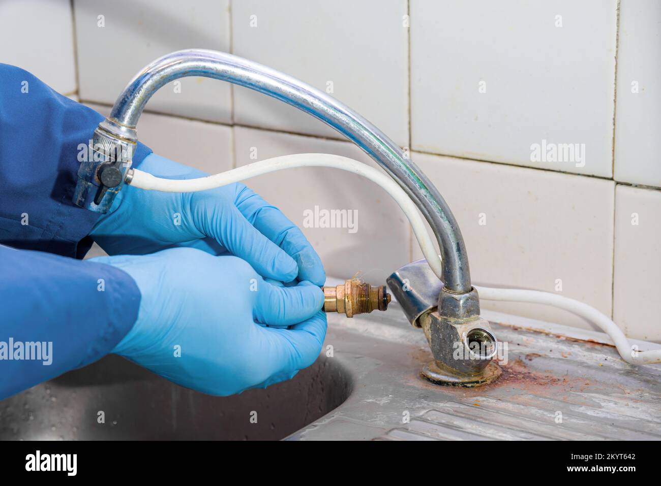 The plumber unscrews the valve from the tap. The master works in ...