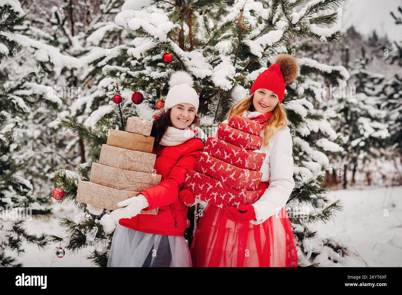 two girls in the winter forest are holding a lot of gifts in their ...