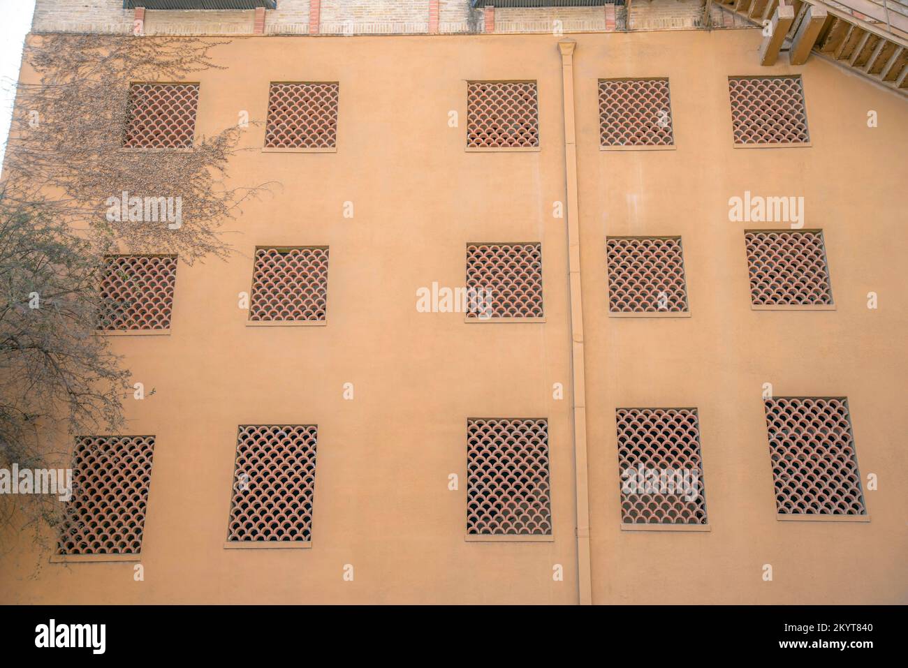Facade of building with square lattice windows and reddish brown wall ...