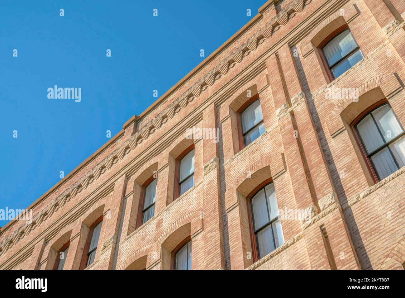 Building exterior with rectangular windows and brick wall against blue ...