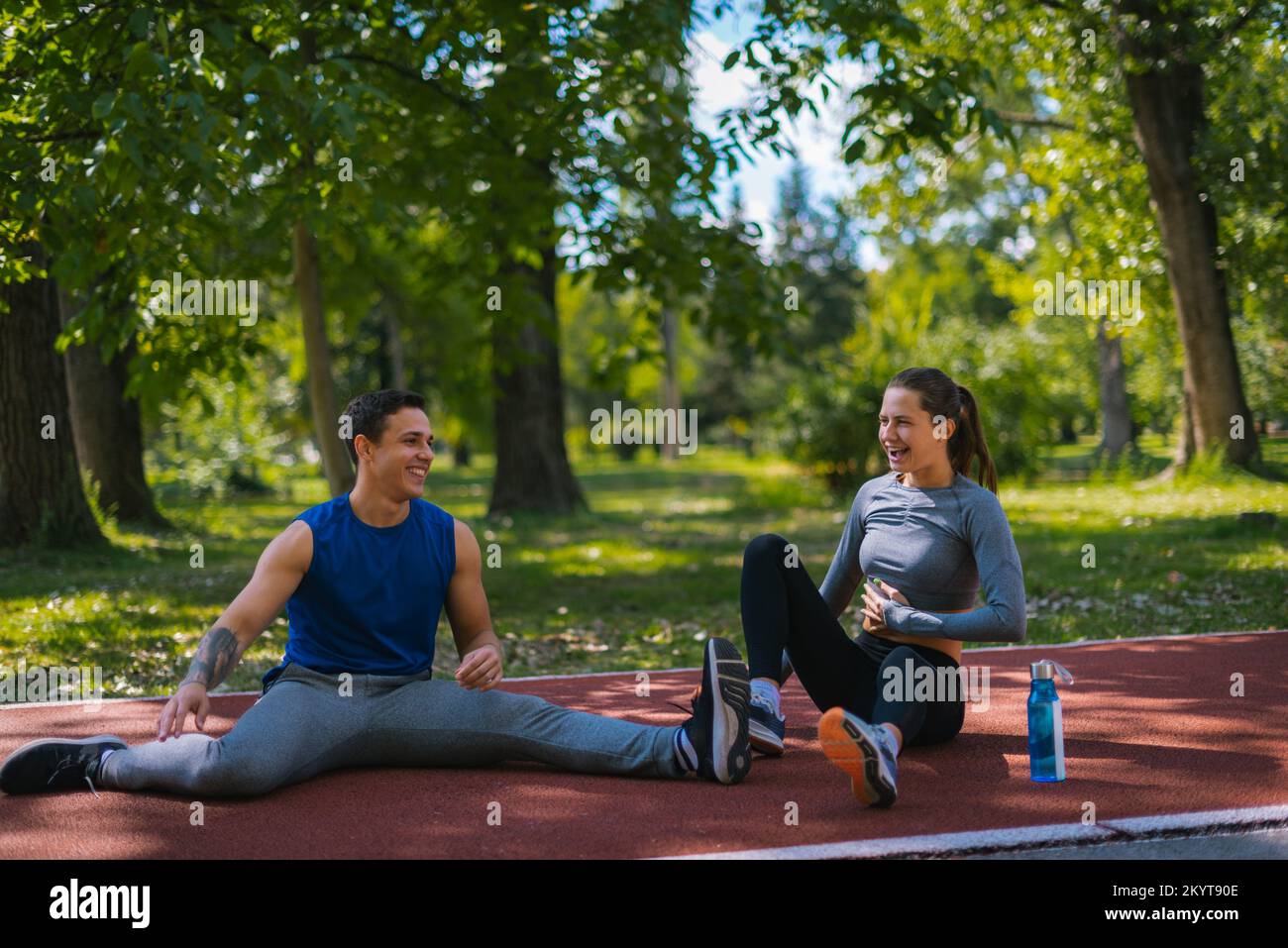 Two young friends exercising together on the runway track at the park ...