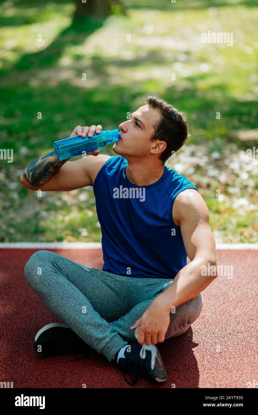 Young sporty male taking a break. Drinking water Stock Photo - Alamy