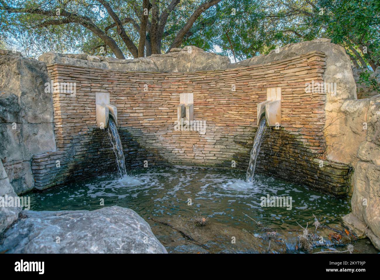 Water fountain with stone brick wall against trees in San Antonio Texas ...